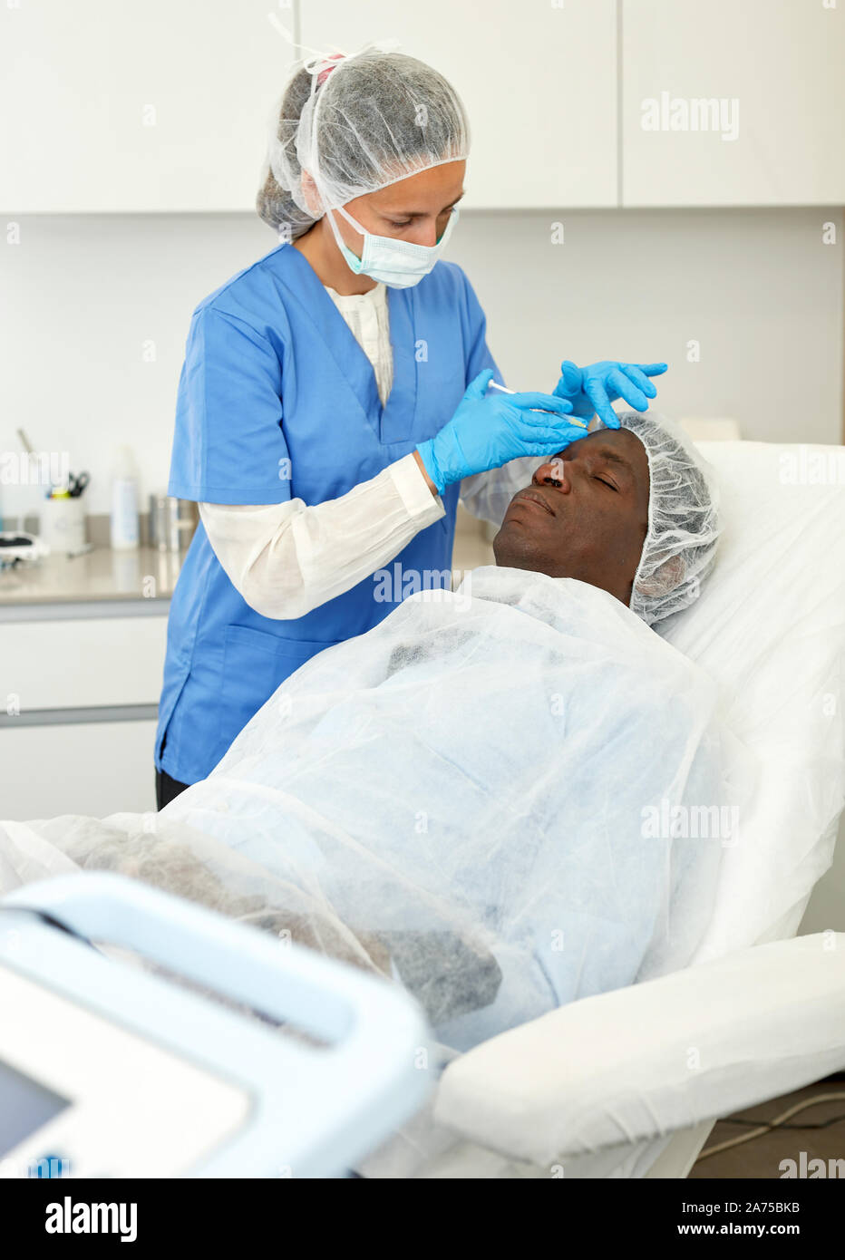 Female doctor examining skin of patient before facial procedure in ...