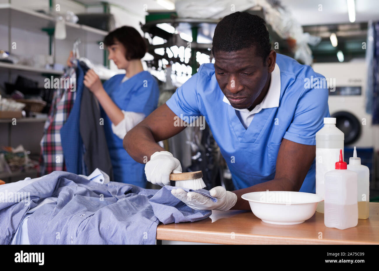 Focused African-American man dry cleaning clothes in laundry Stock ...