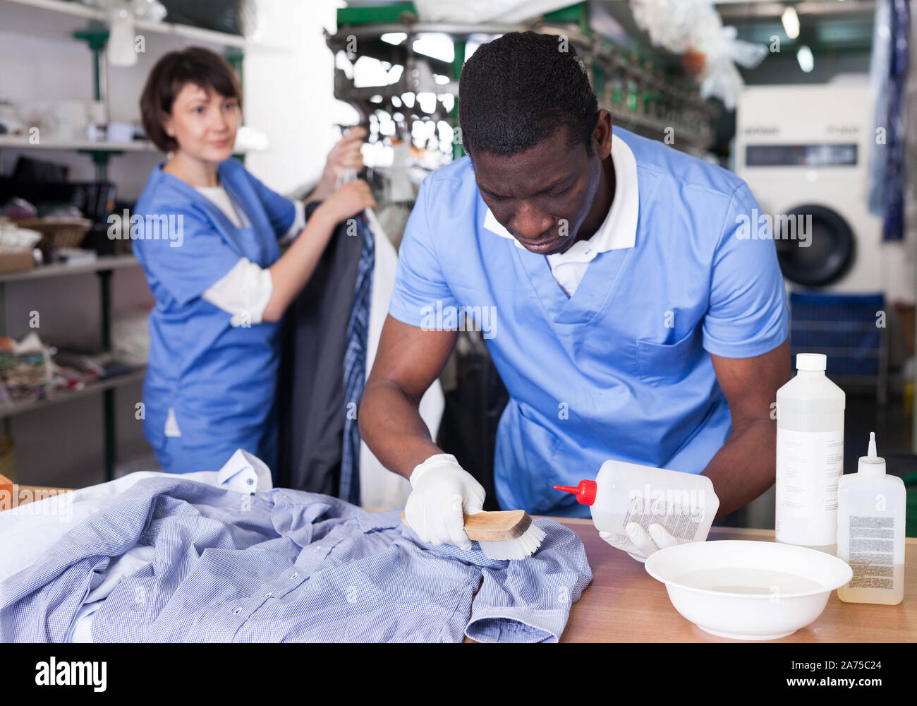 Focused African-American man dry cleaning clothes in laundry Stock ...