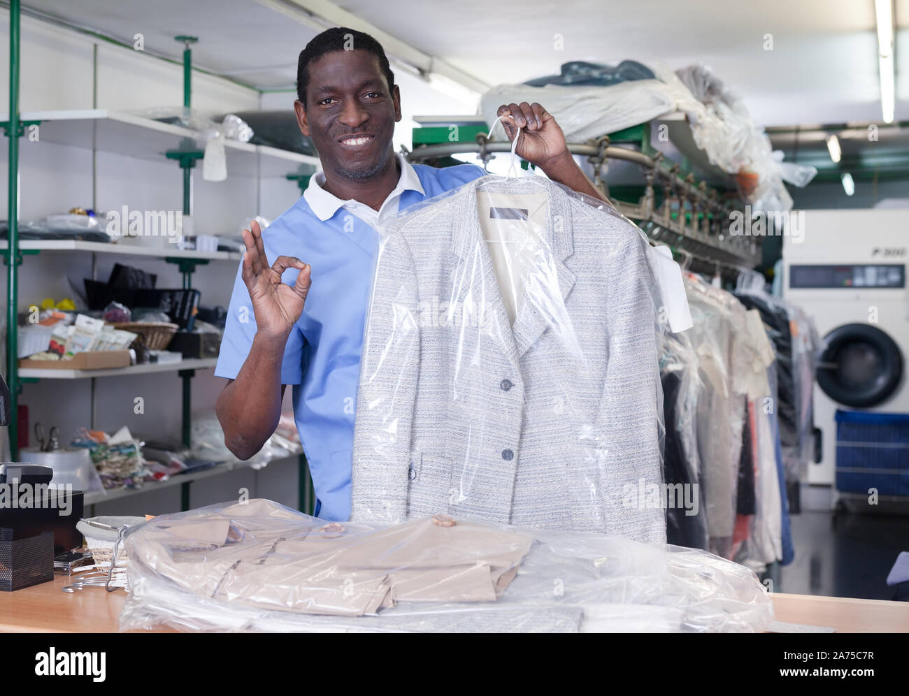 Cheerful African American man worker of dry cleaner standing at ...