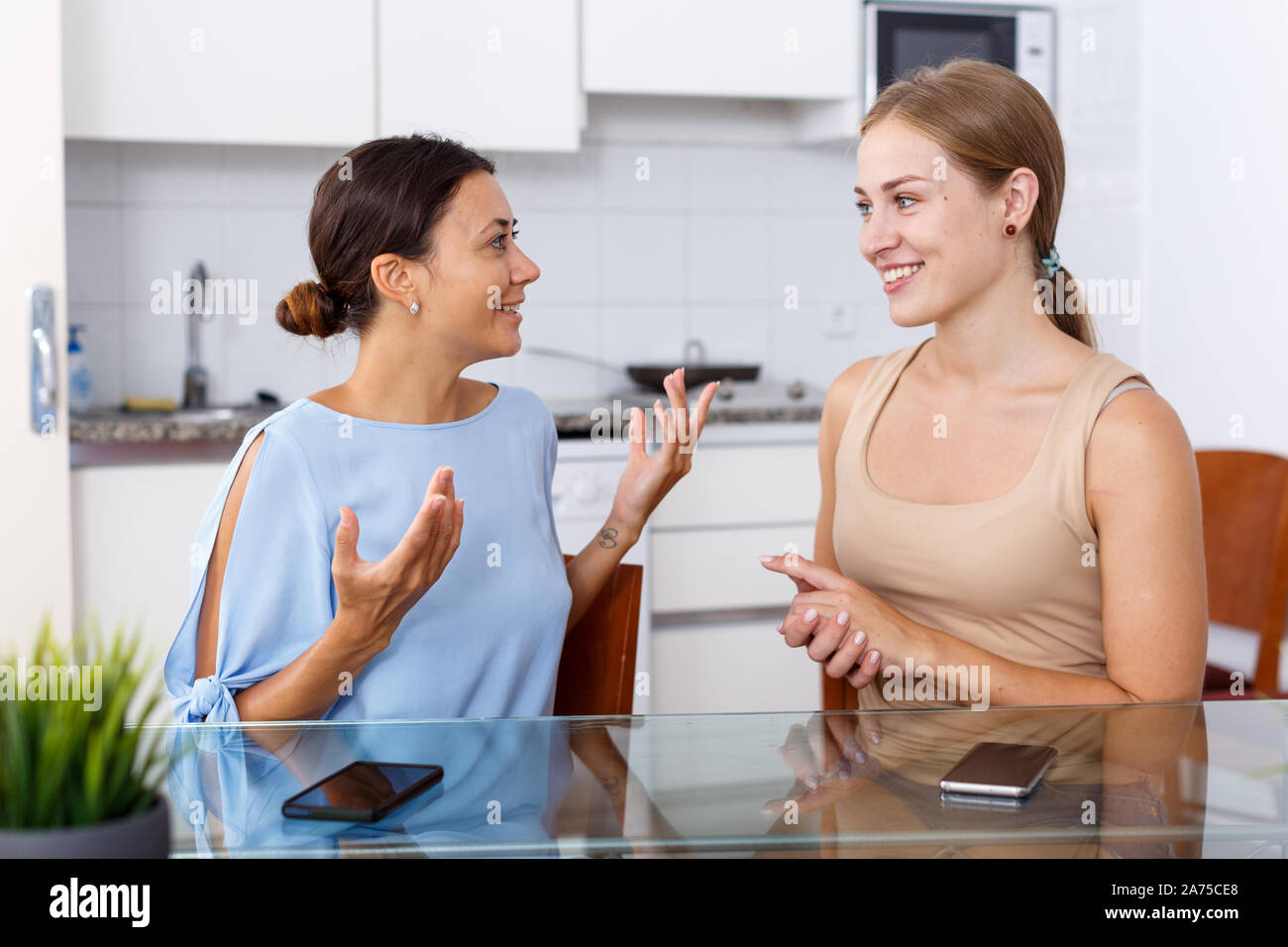 Two friendly girls having emotional conversation in kitchen interior ...
