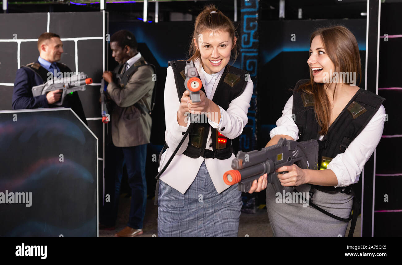 Emotional portrait of two glad women holding laser pistols and playing ...