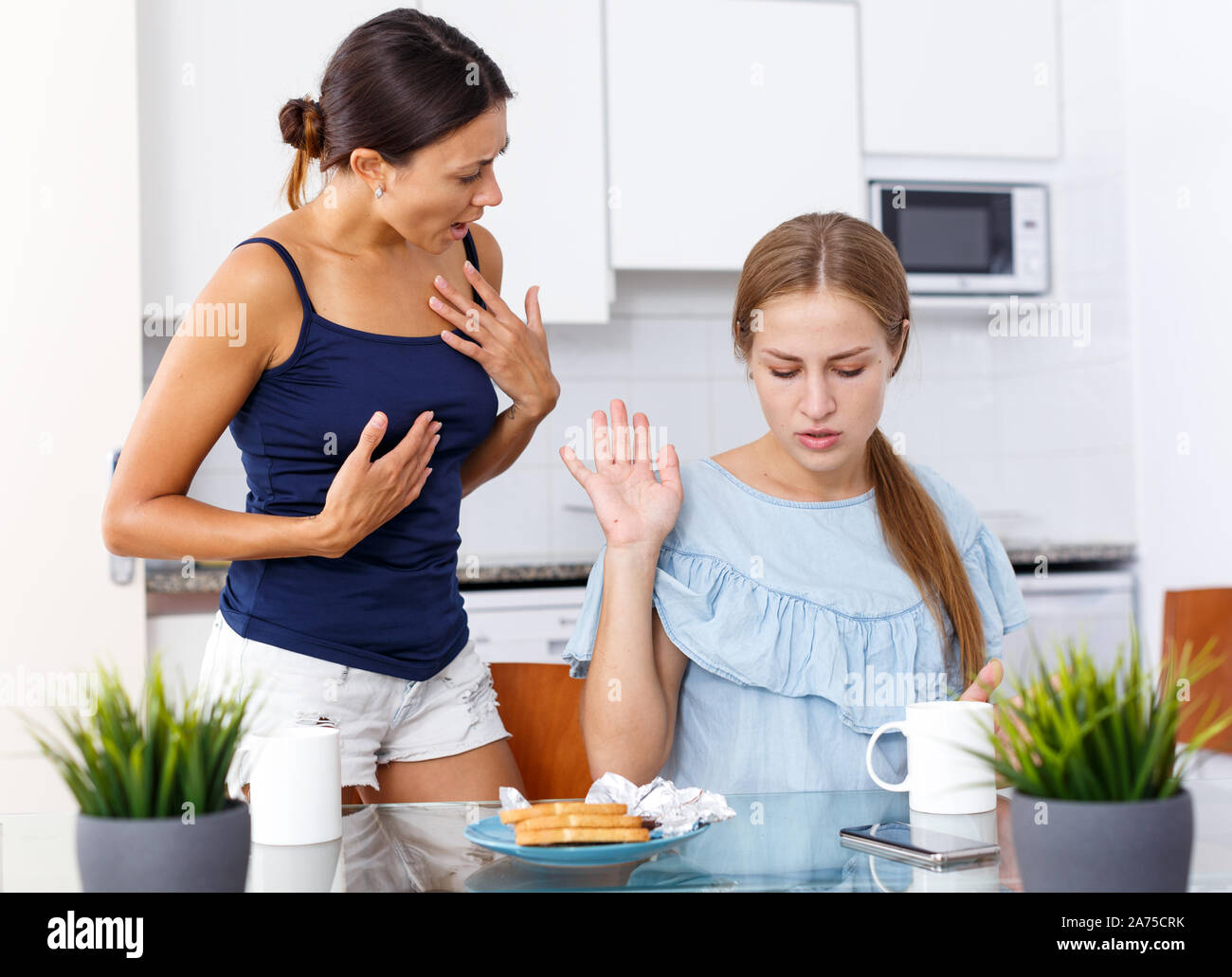 Emotional quarrel between two young women friends in kitchen interior ...