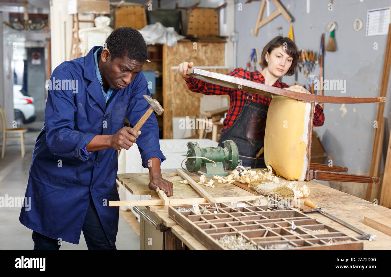 Woman and man carpenters using tools for restoration wooden chair in ...