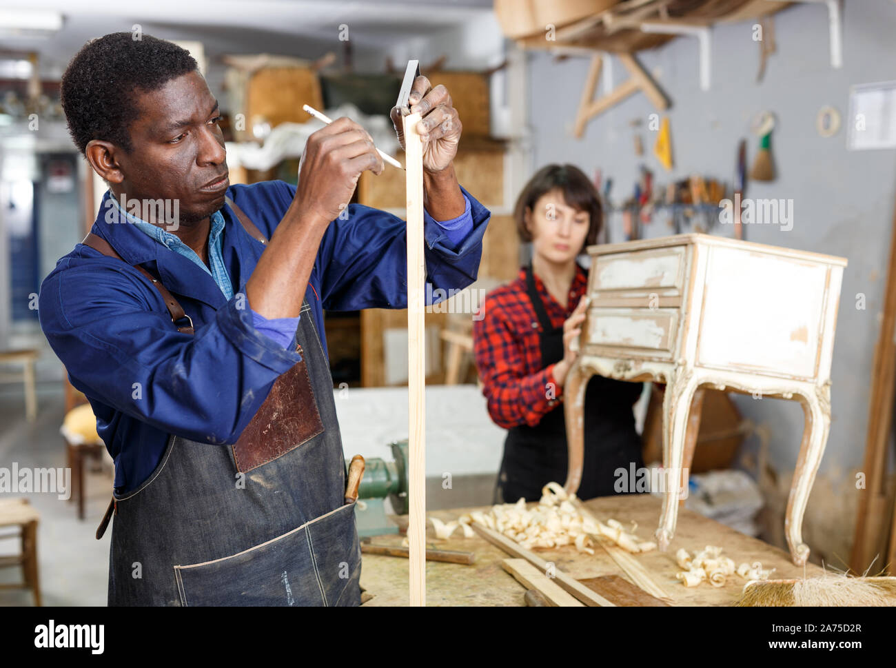 Woman and man carpenters using tools for restoration wooden bureau in ...