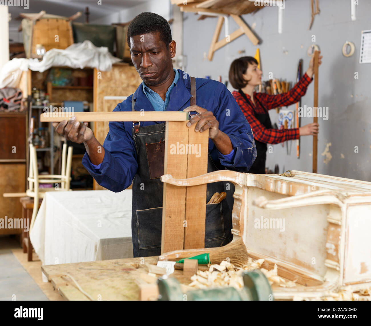 Woman and man carpenters using tools for restoration wooden bureau in ...