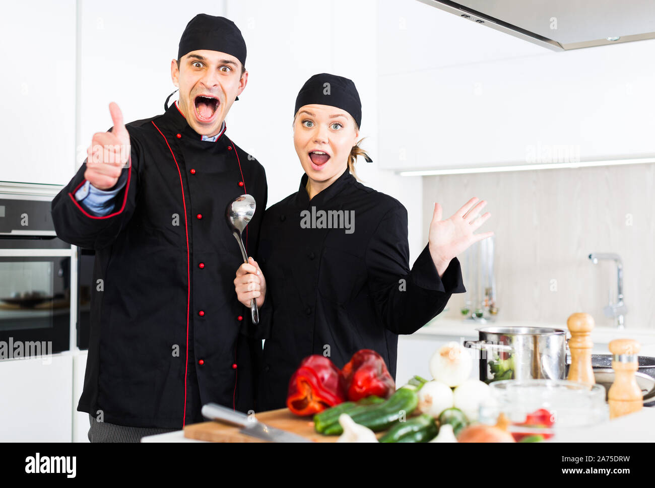 Portrait of female and male cooks who are standing with devices on ...