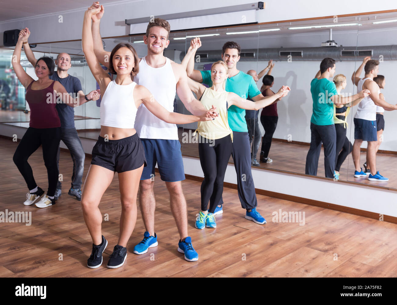 Group of smiling people dancing salsa together in dance studio Stock ...