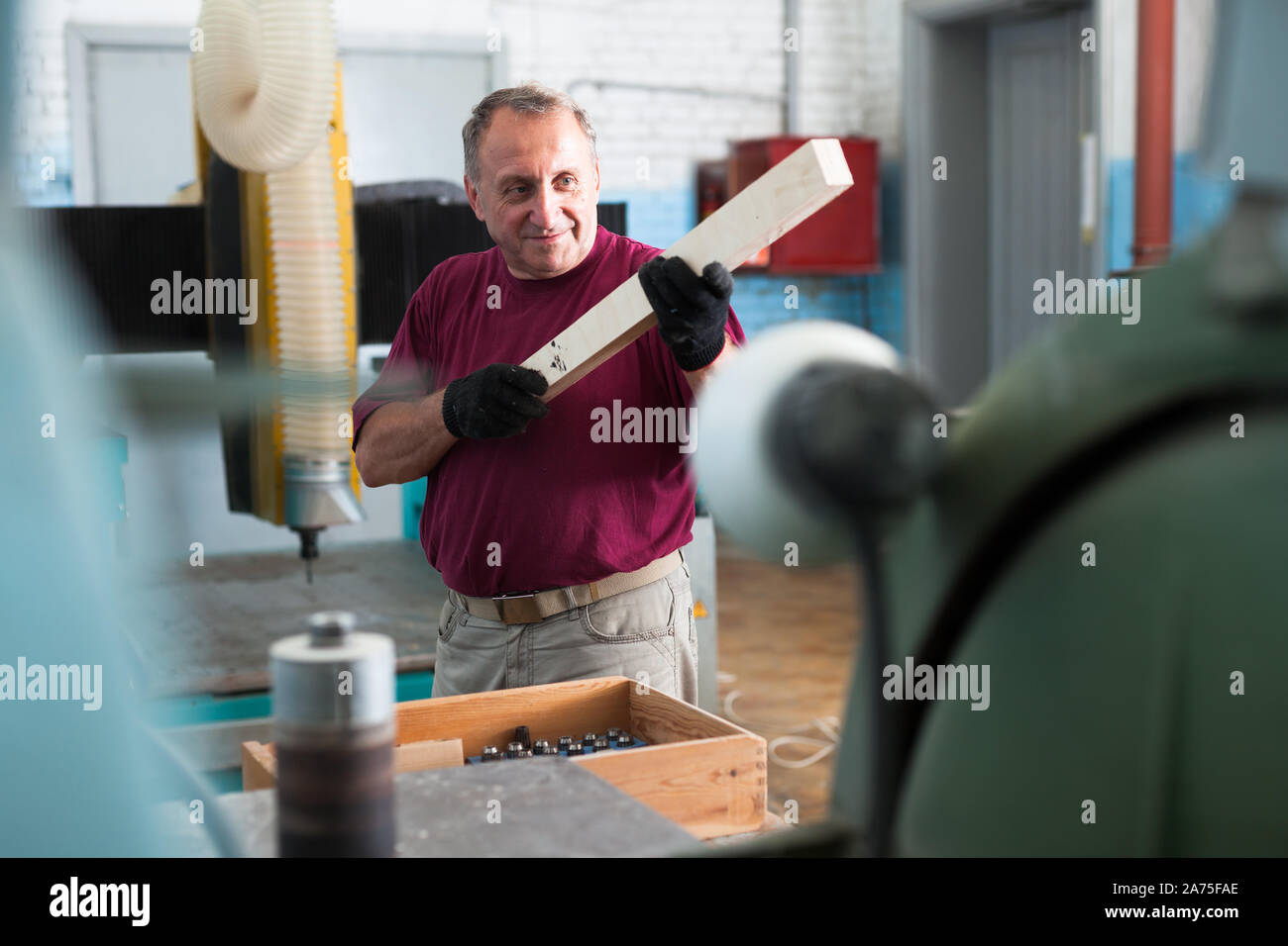 Concentrated worker is shaping timber on woodworking machine at the ...