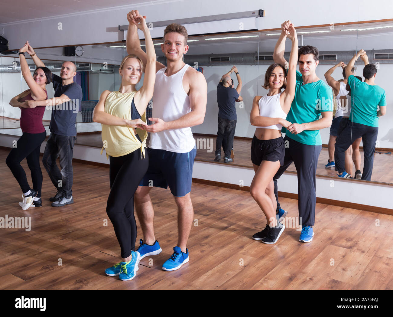 Group of active adults dancing salsa together in dance studio and ...