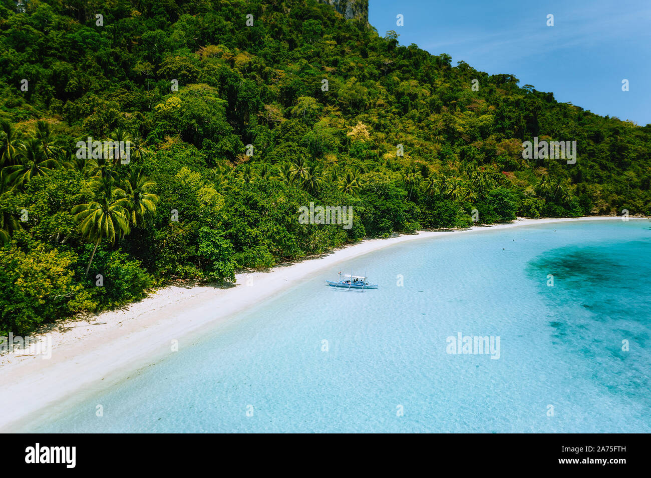 Aerial view of tropical boat moored at secluded white sand beach with ...