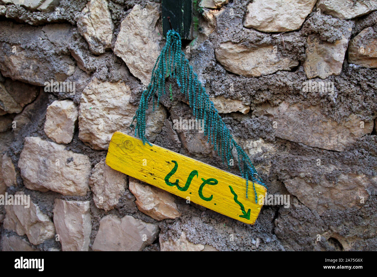 WC sign indication on beach. Yellow wooden billboard with toilet sign ...