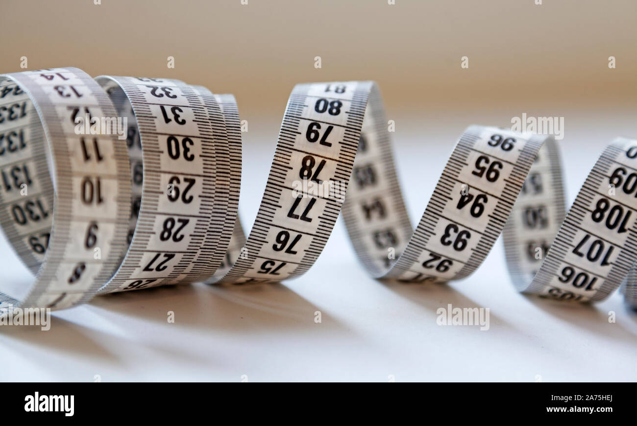 a white tape measure lying in a tangled spiral on the table Stock Photo ...