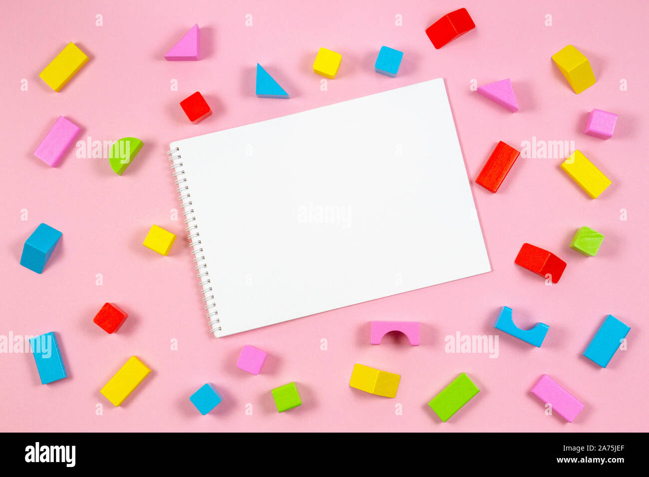 Colorful wooden building blocks and white blank open notebook on pink ...