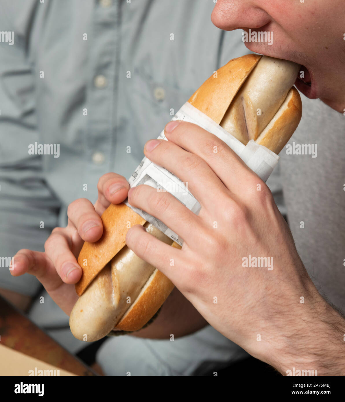 Man eating sausage sandwich in a restaurant Stock Photo - Alamy