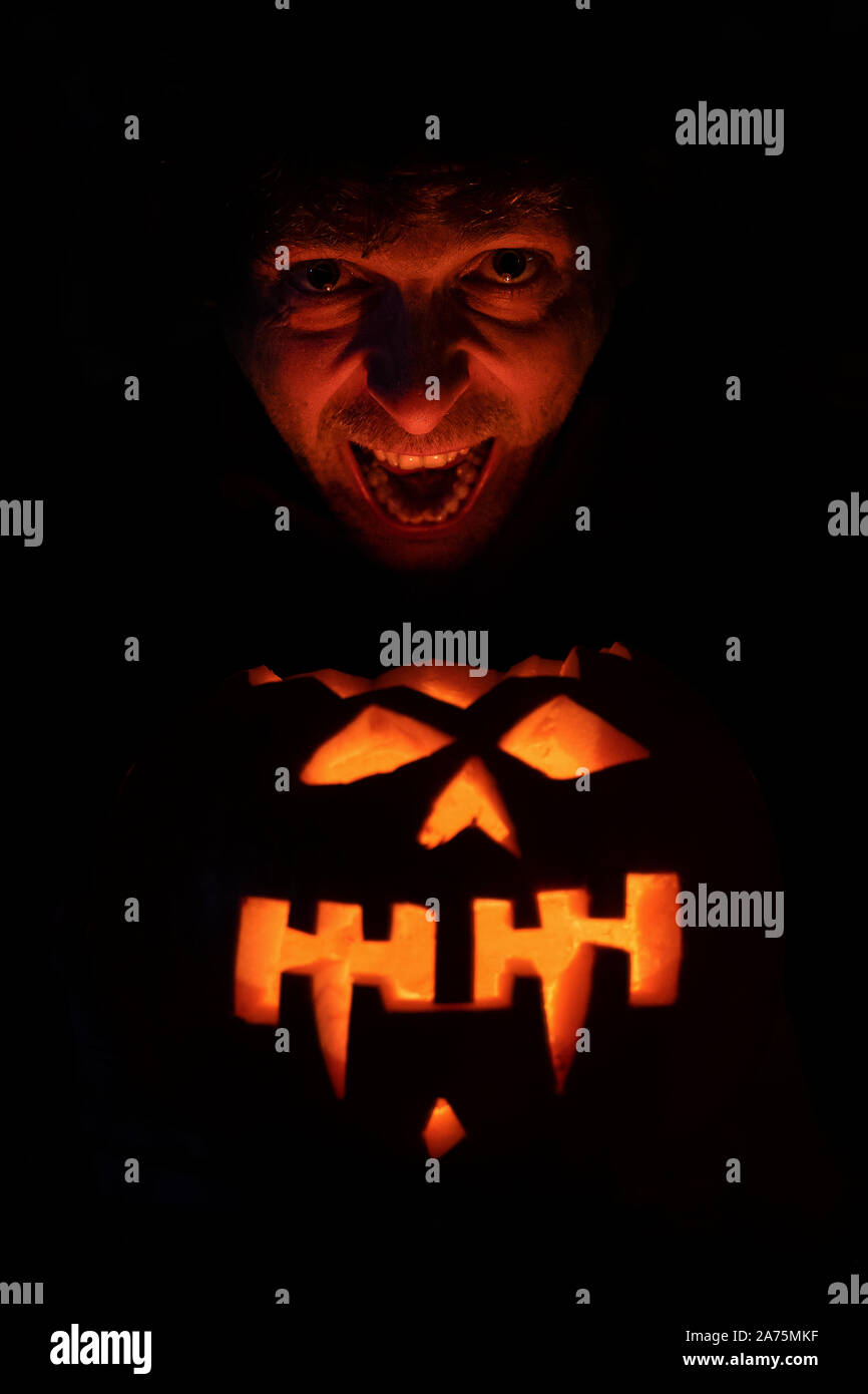 Scary face lit by Halloween pumpkin. Evil Laughing. Human Face Stock ...