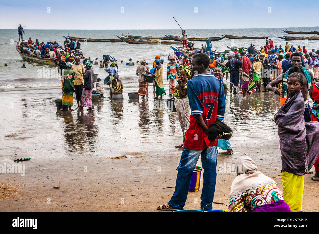 People crowd onto the beach in Tanji Fishing Village in The Gambia as ...
