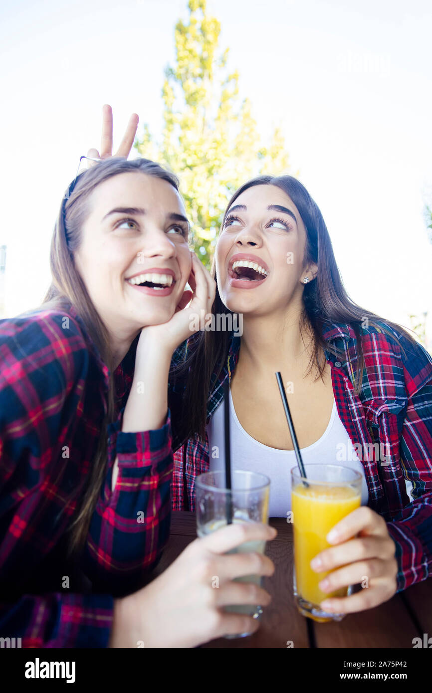 Two young women drinking juice and lemonade in the park at sunny day ...