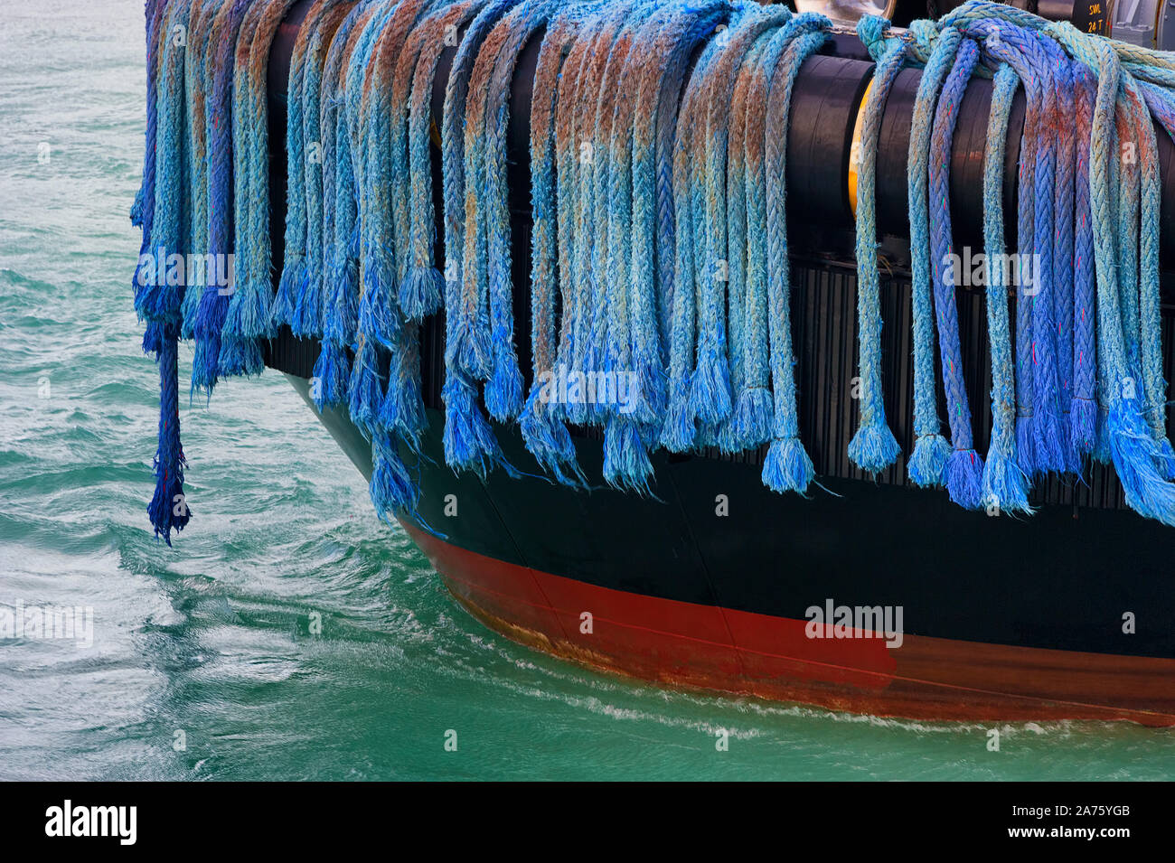 Close up of rope draped over rubber bumper of a tug boat as an extra ...