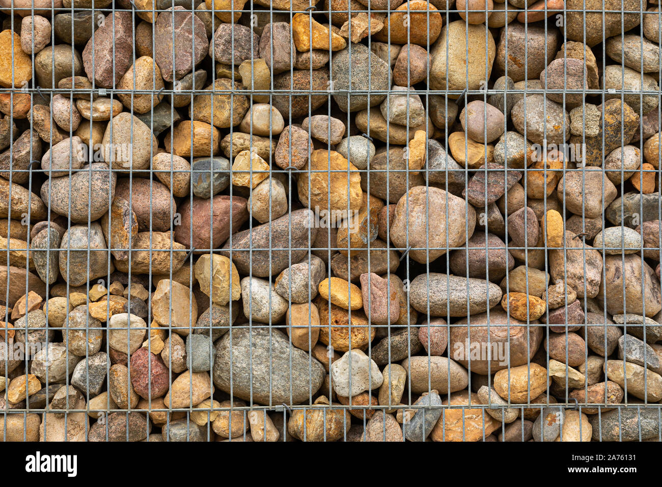 Mass of colorful cobblestones laying behind metal lattice work Stock ...