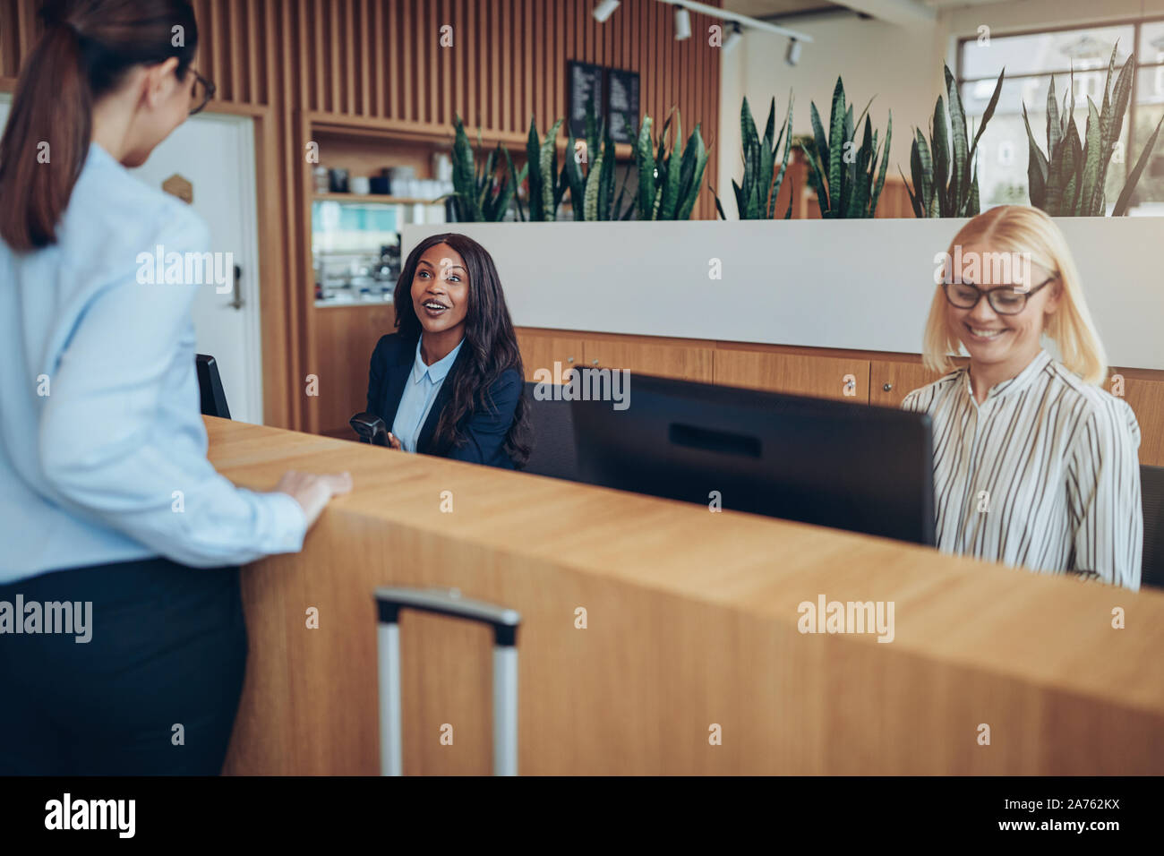 Smiling young African American concierge sitting behind the reception ...