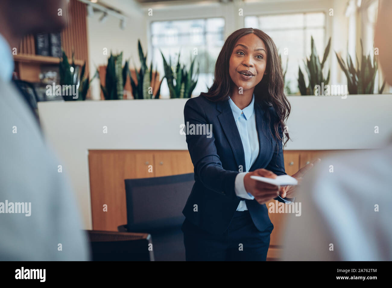 Smiling young African American concierge helping two guests check in ...
