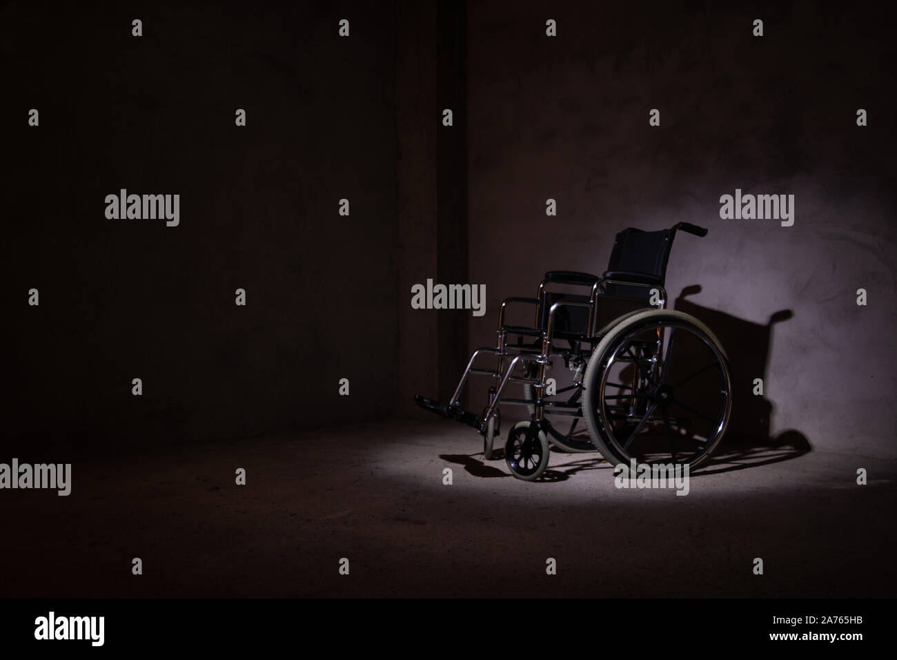 An isolated wheelchair illuminated with a light in the dark. Disability ...