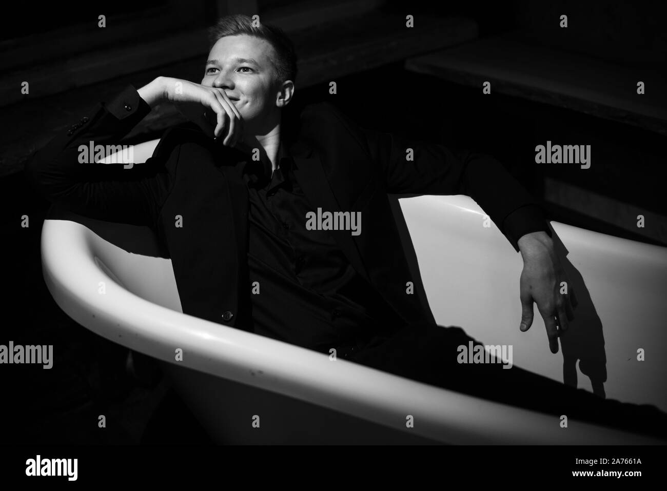 Man in black clothes is lying in empty bath Stock Photo - Alamy