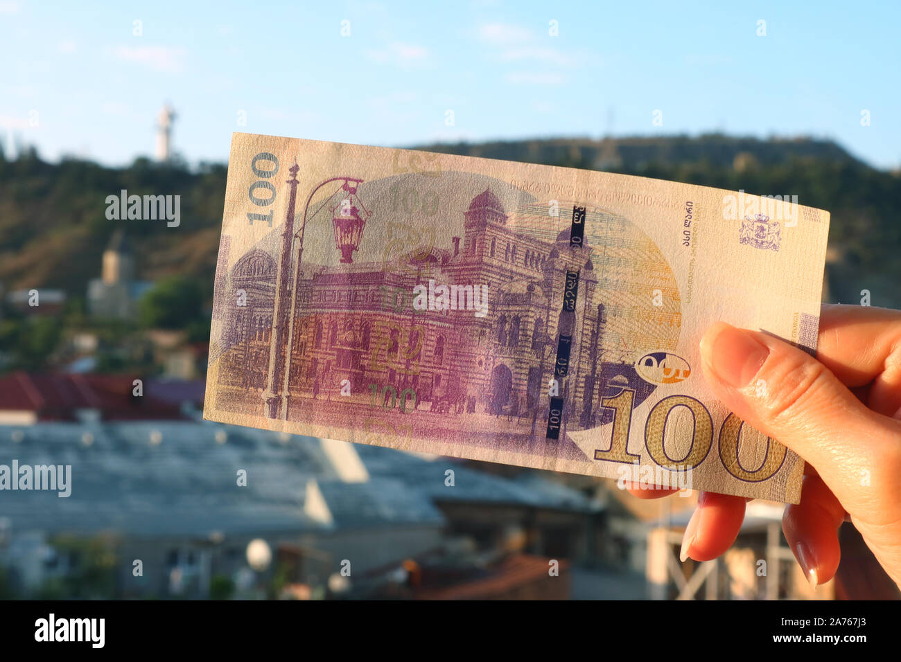 The Reverse Side of Georgian 100 Lari banknote in Woman's Hand with ...