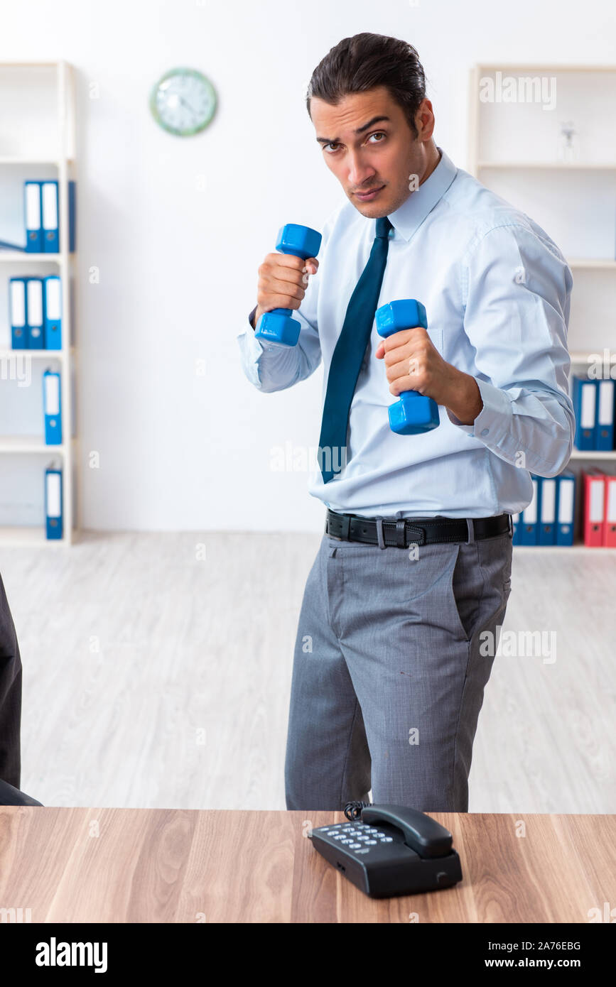 The young handsome employee doing sport exercises at workplace Stock ...