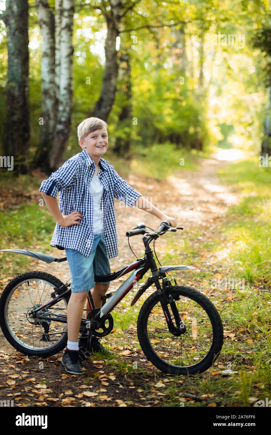 Boy in countryside riding bike in summer park smiling at camera Stock ...