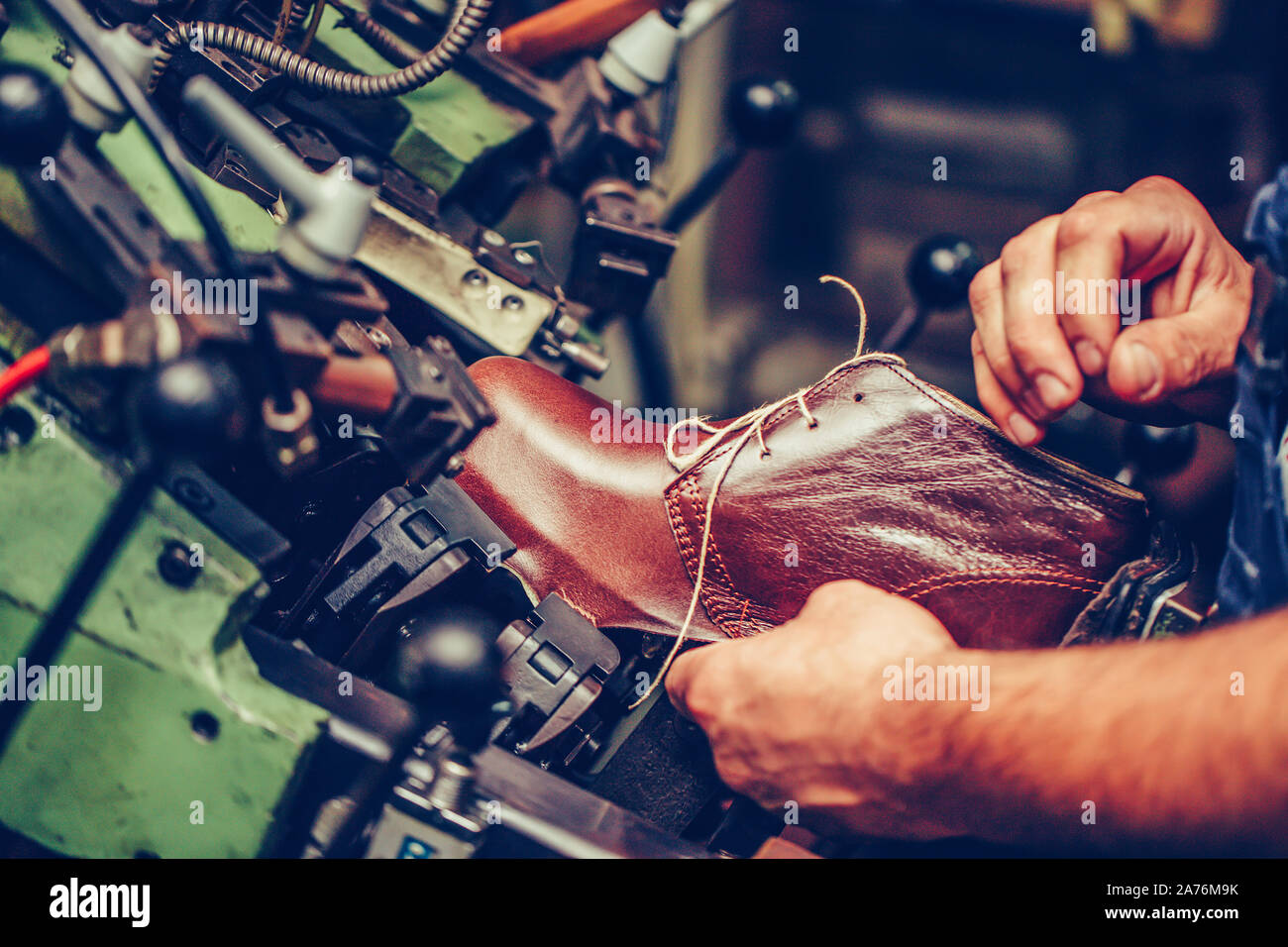 Experienced shoemaker using a special machine for putting shoes on the ...