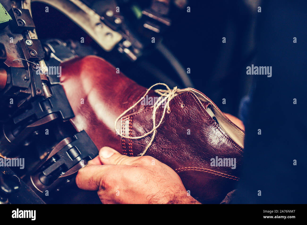 Experienced shoemaker using a special machine for putting shoes on the ...