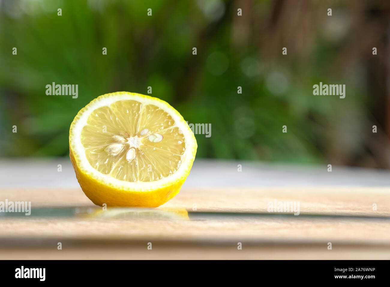 Lemon cut into half on a wooden table with green nature background ...