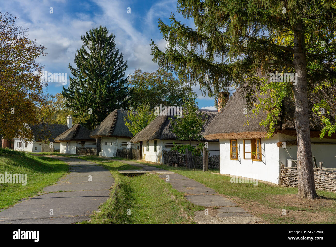 Historical old hungarian village with straw roof houses and a bench ...