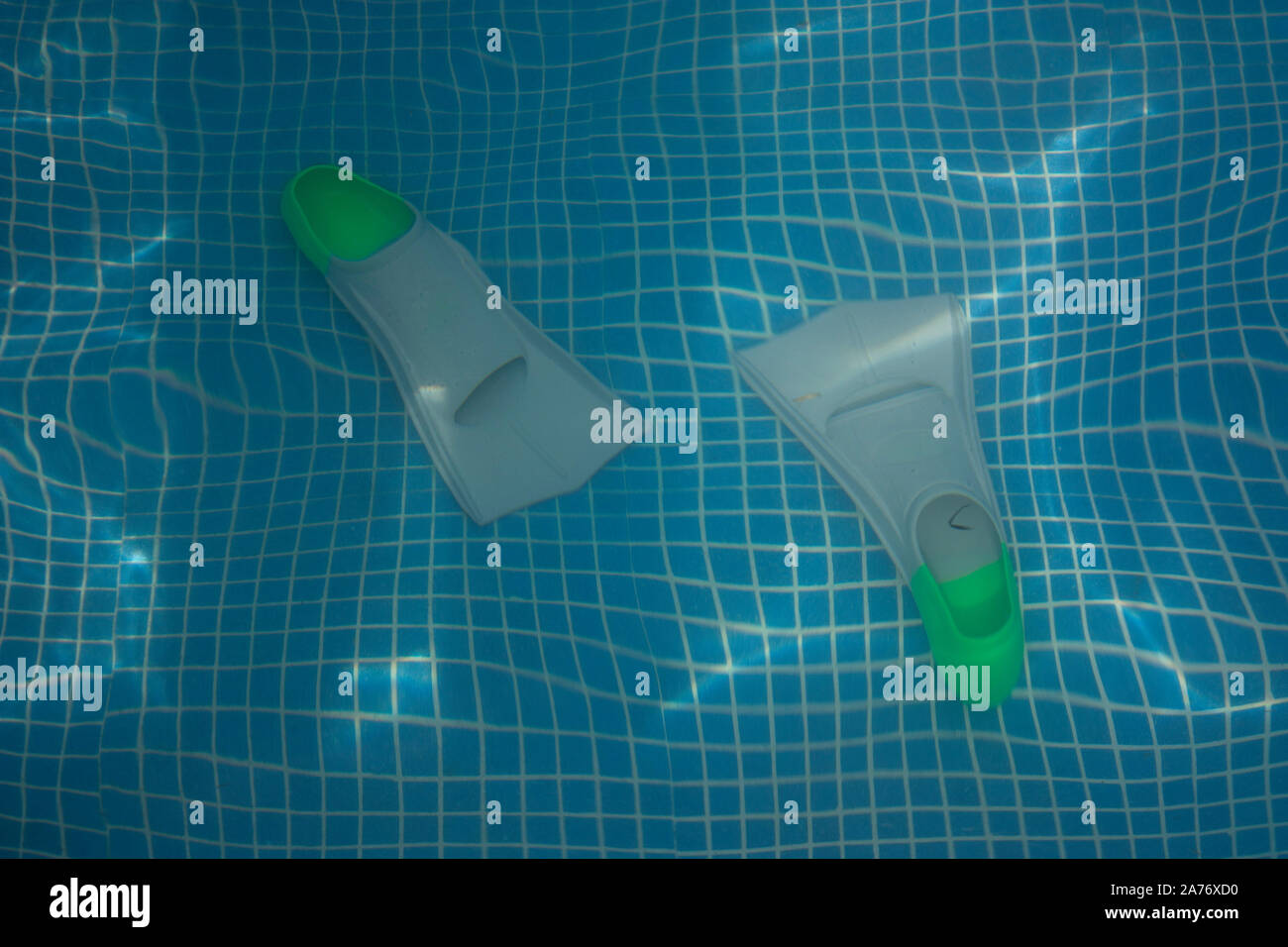 Fins at the bottom of a pool between the mosaics that with the water ...