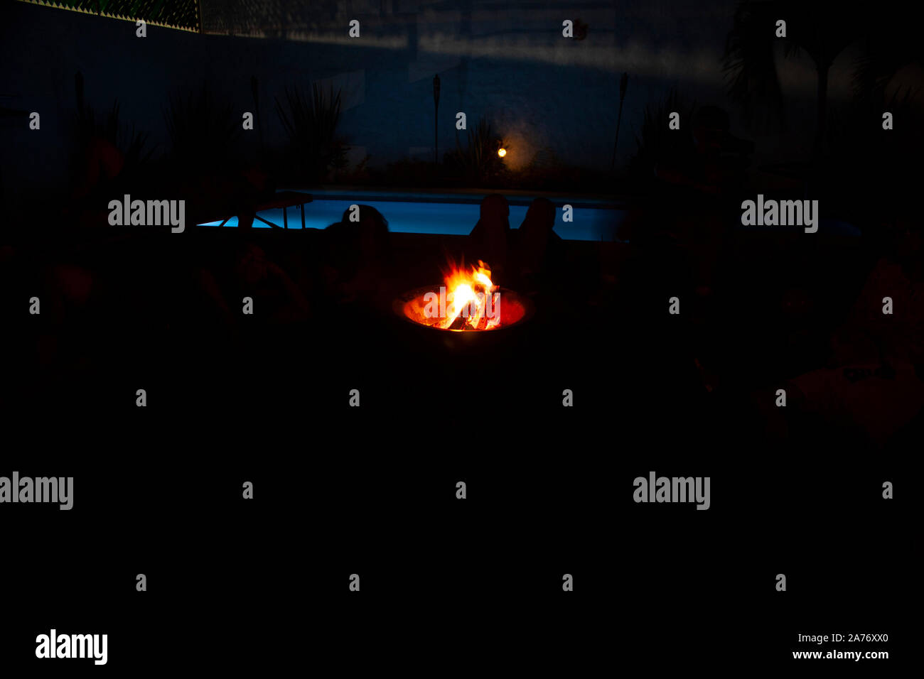Silhouettes of people surrounding the bonfire that has been made by the ...