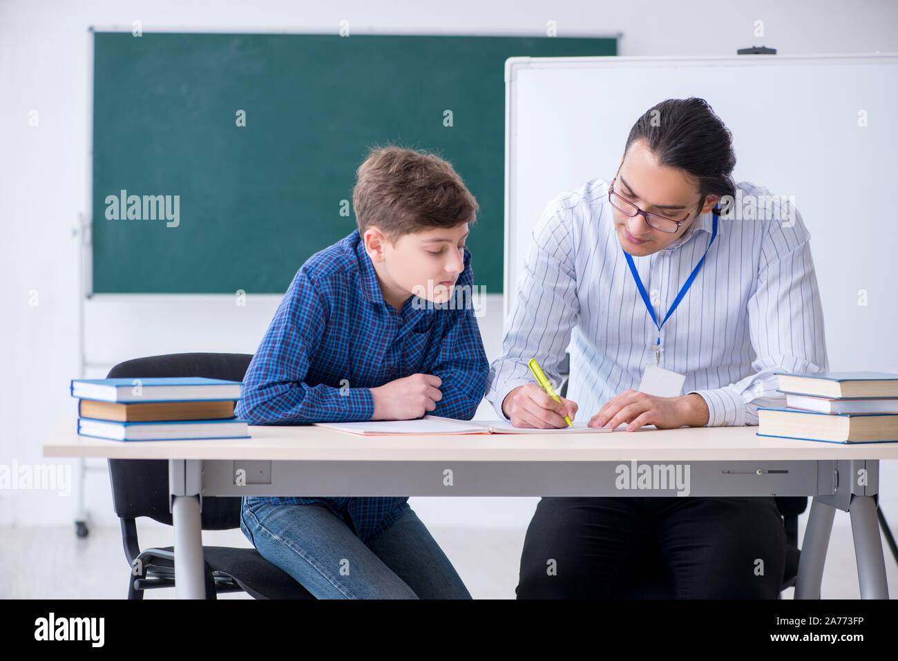 The young male teacher and boy in the classroom Stock Photo - Alamy