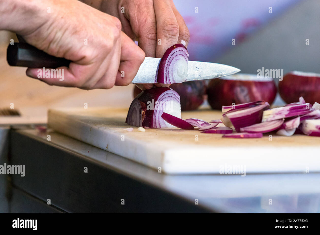 Male hand cutting - chopping red onions, sun light Stock Photo - Alamy