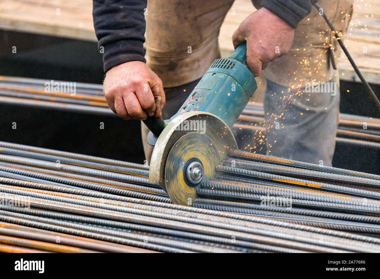 Male hands cutting steel bars with a circular electric grinder Stock ...