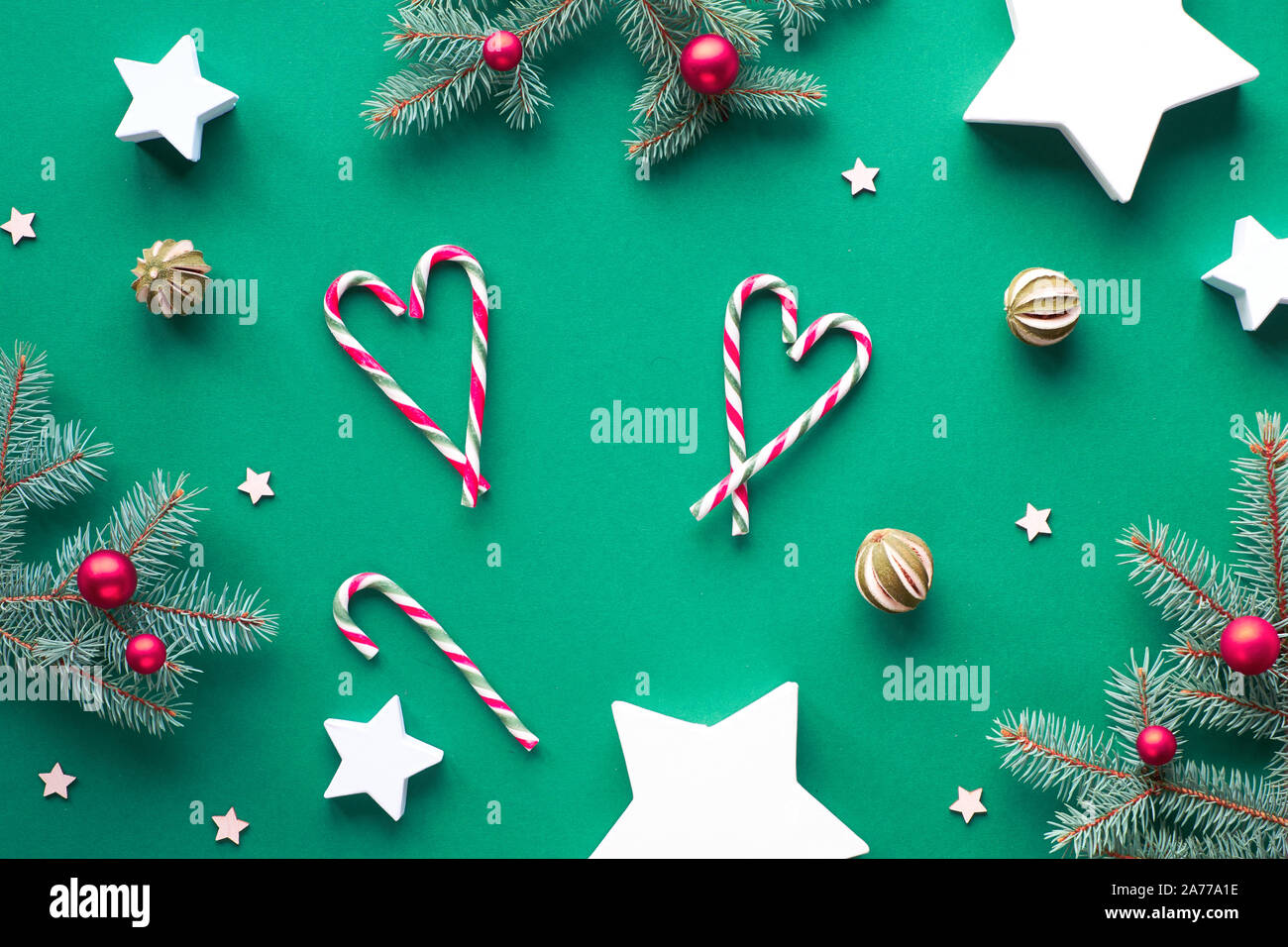 Creative Christmas flat lay with fir twigs, candy canes arranged as hearts, red glass baubles ...