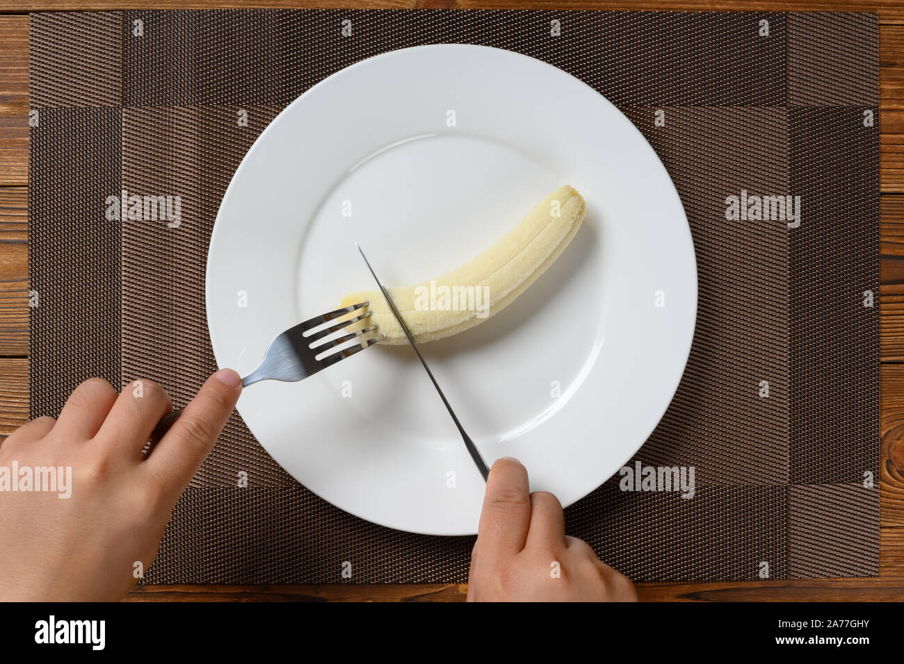 top view man eating a fresh banana with fork and knife Stock Photo - Alamy