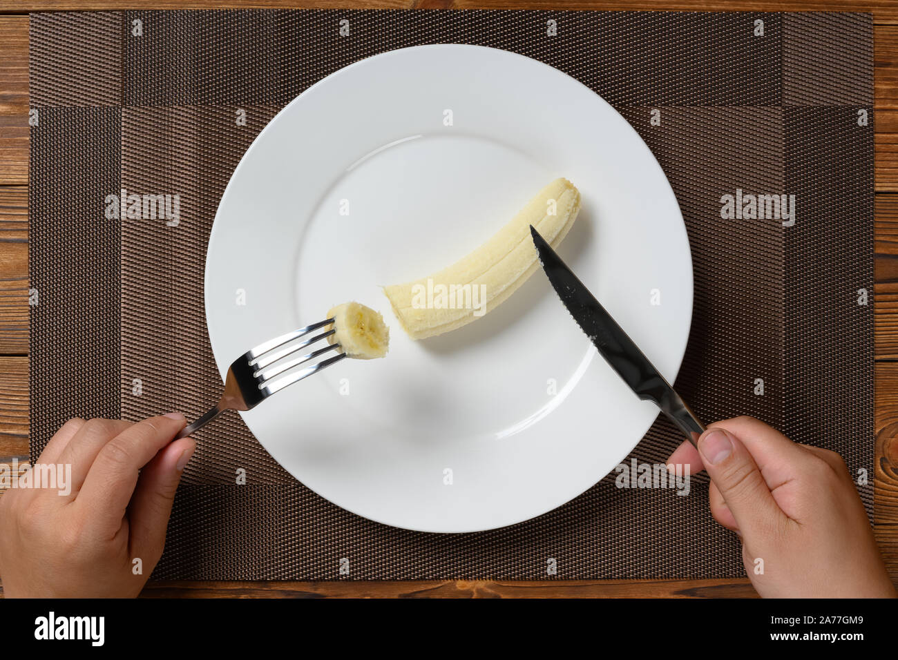 top view man eating a fresh banana with fork and knife Stock Photo - Alamy