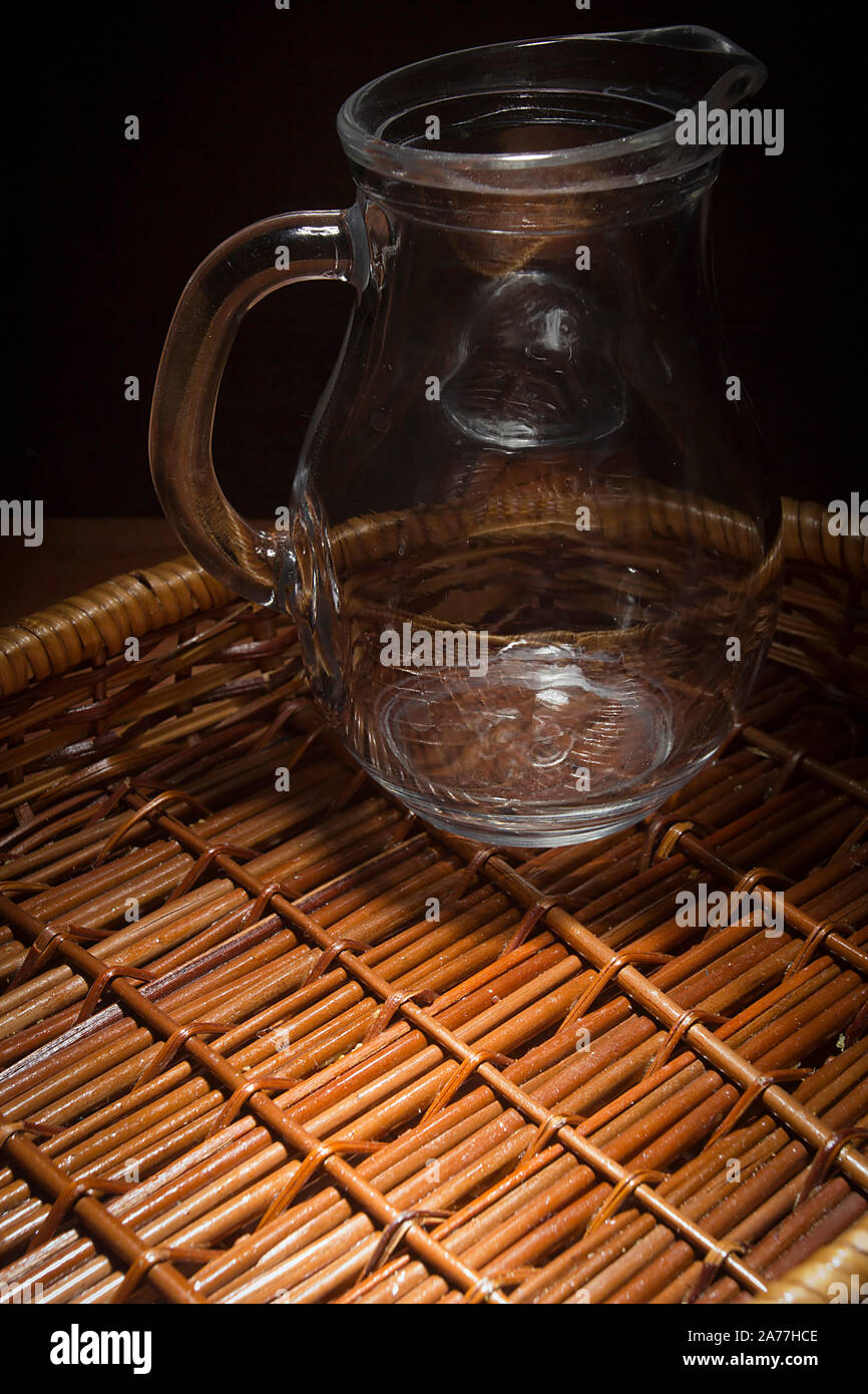 Empty glass jug in a wicker basket Stock Photo - Alamy