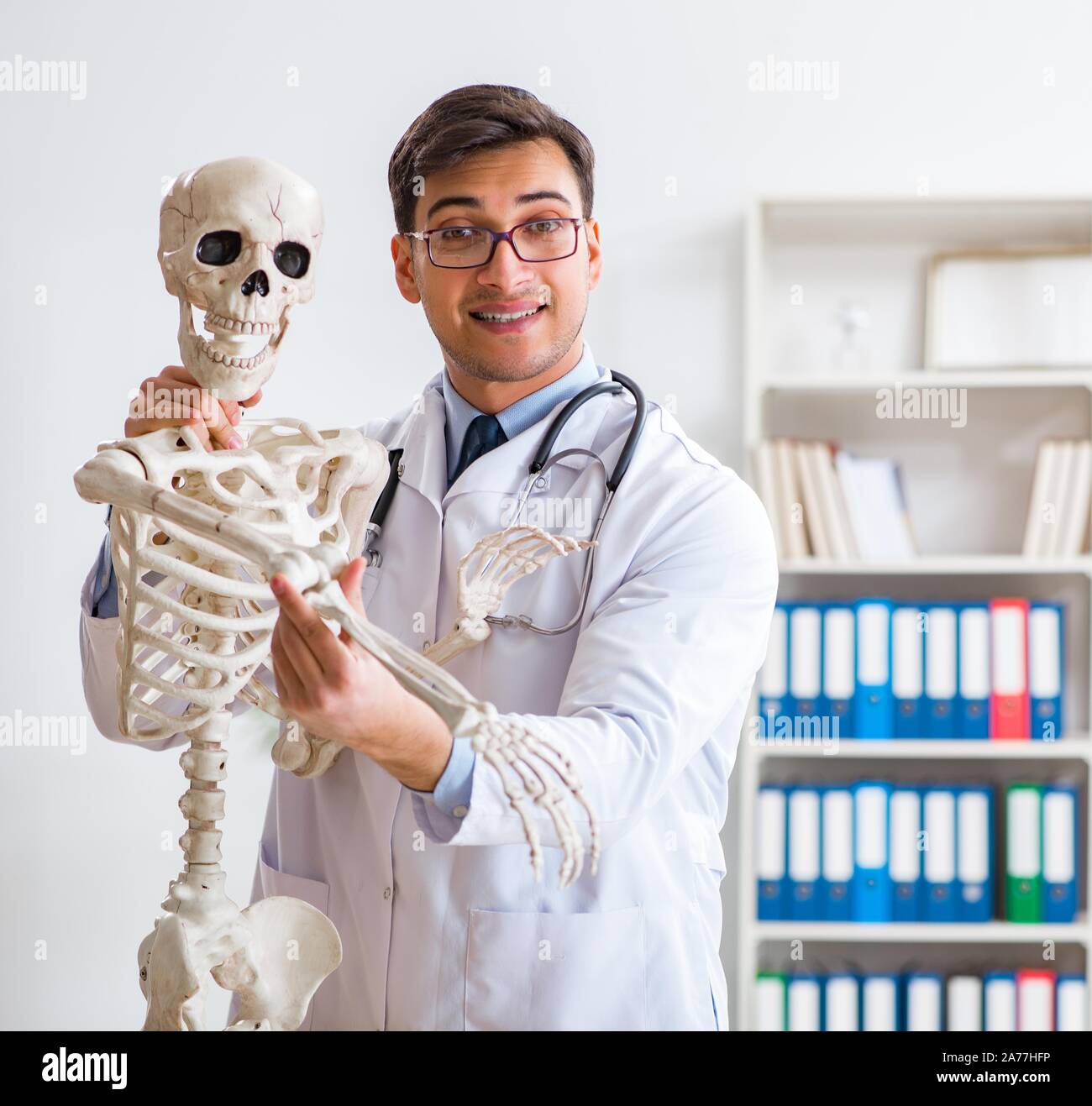 The yong male doctor with skeleton isolated on white Stock Photo - Alamy