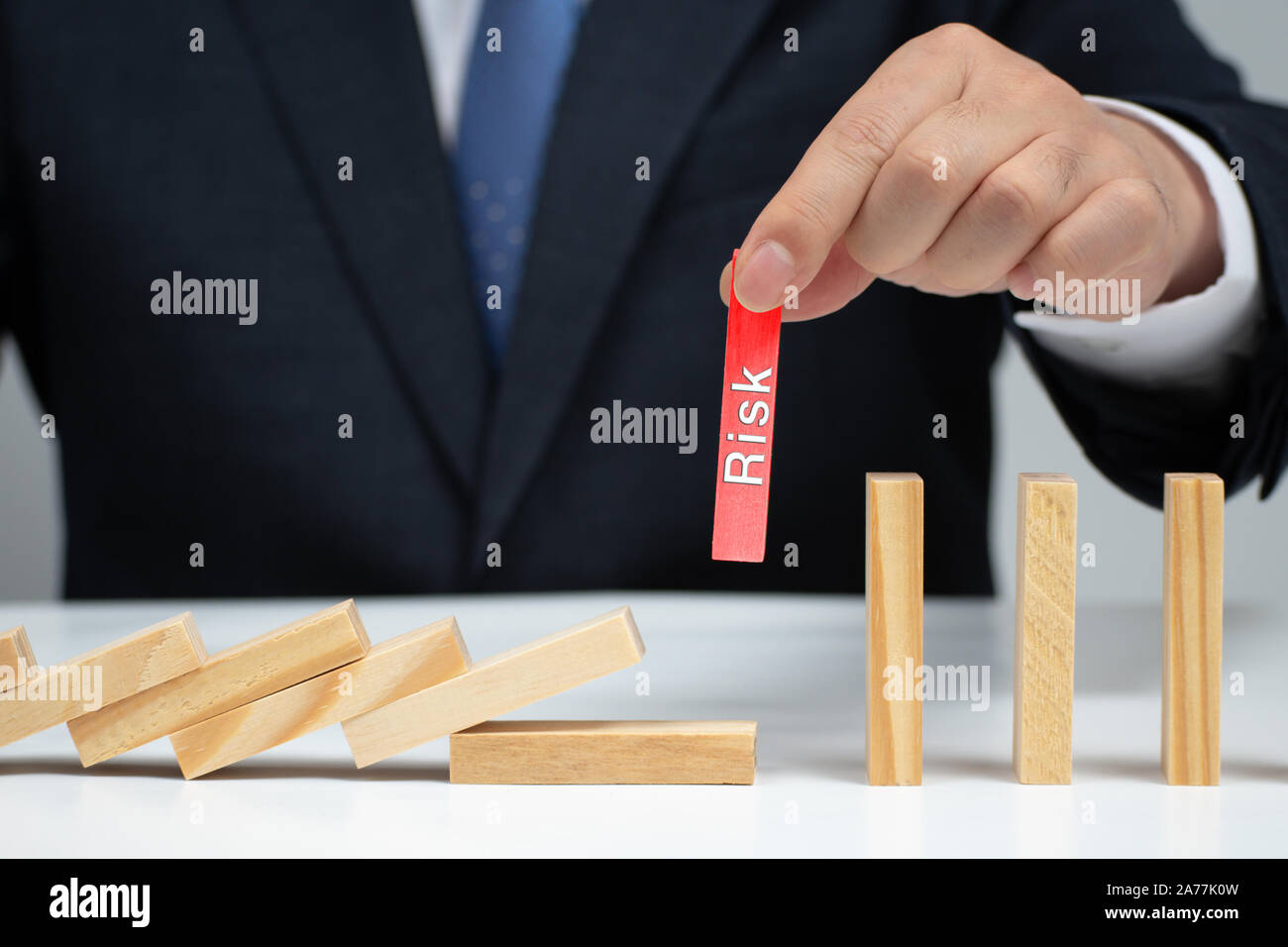 Male hand stopping the domino effect. Risk control concept Stock Photo ...