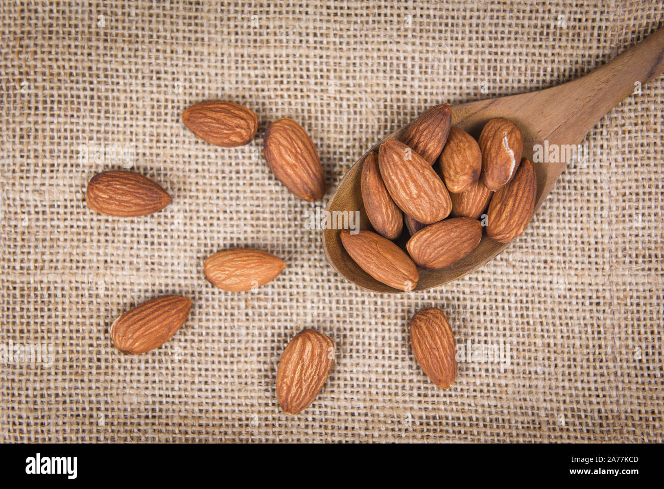 Almonds on wooden spoon and sack background top view / Close up almond ...