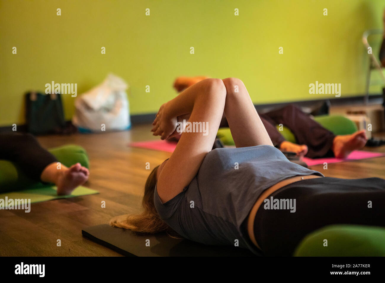 Back view of a female yoga instructor who is giving a yoga session to a ...