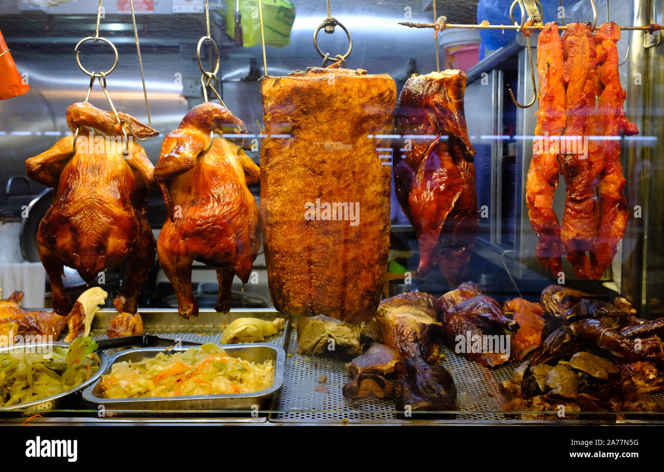 Cooked chickens and pork on display at a local food market in Singapore ...