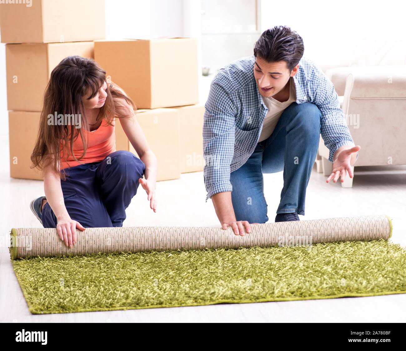 The young family rolling carpet at new apartment Stock Photo - Alamy